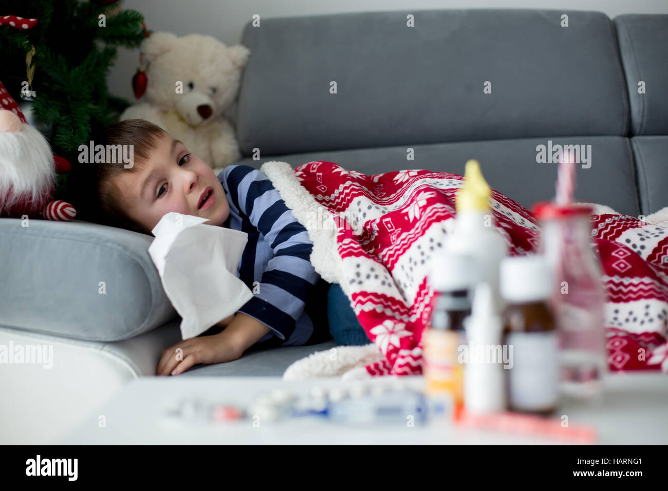 Sick little child, boy, with high fever sleeping on the couch at home ...