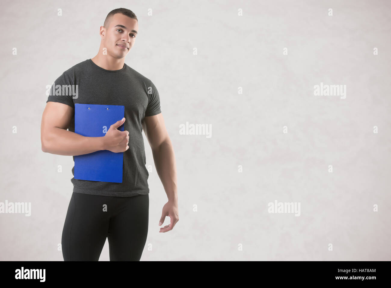 Personal Trainer, with a pad in his hand, isolated in grey Stock Photo ...