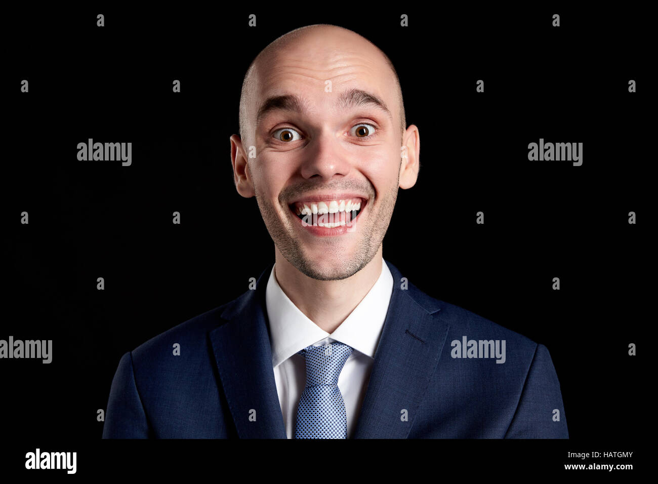 Studio portrait of young crazy smiling man against black background ...
