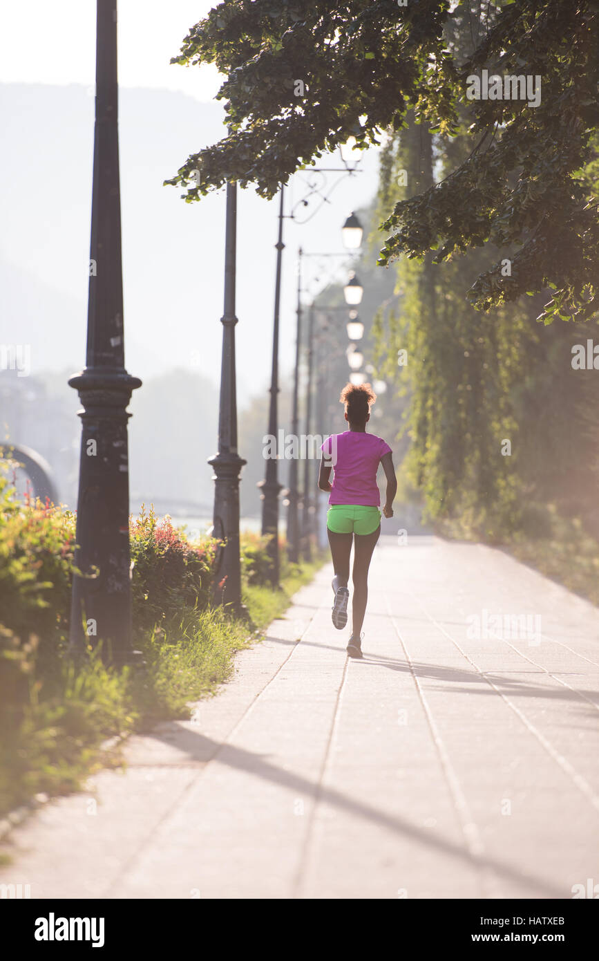 Beautiful young sporty african american woman running at early morning ...