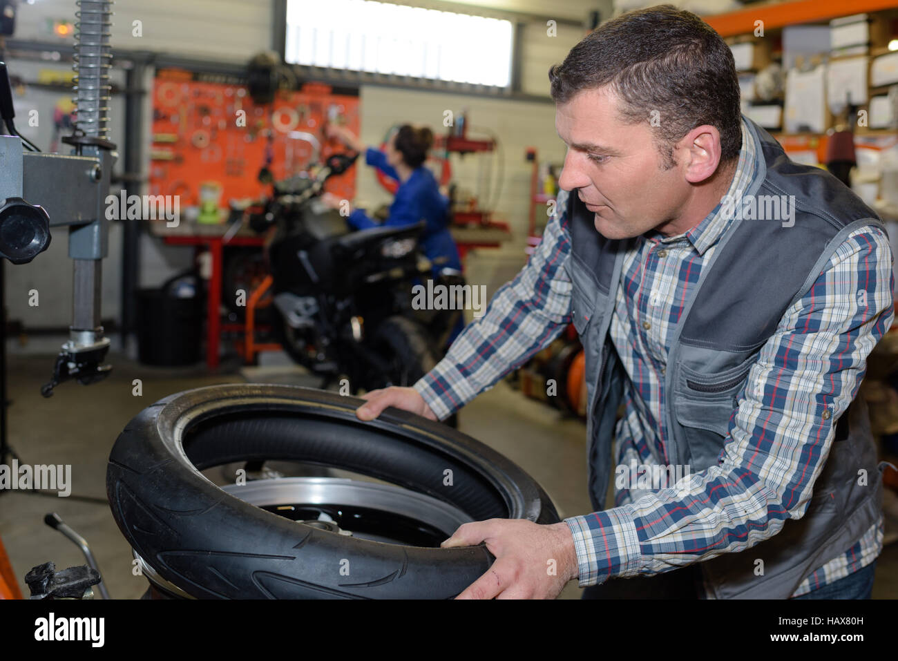 Mechanic holding scooter tyre Stock Photo - Alamy