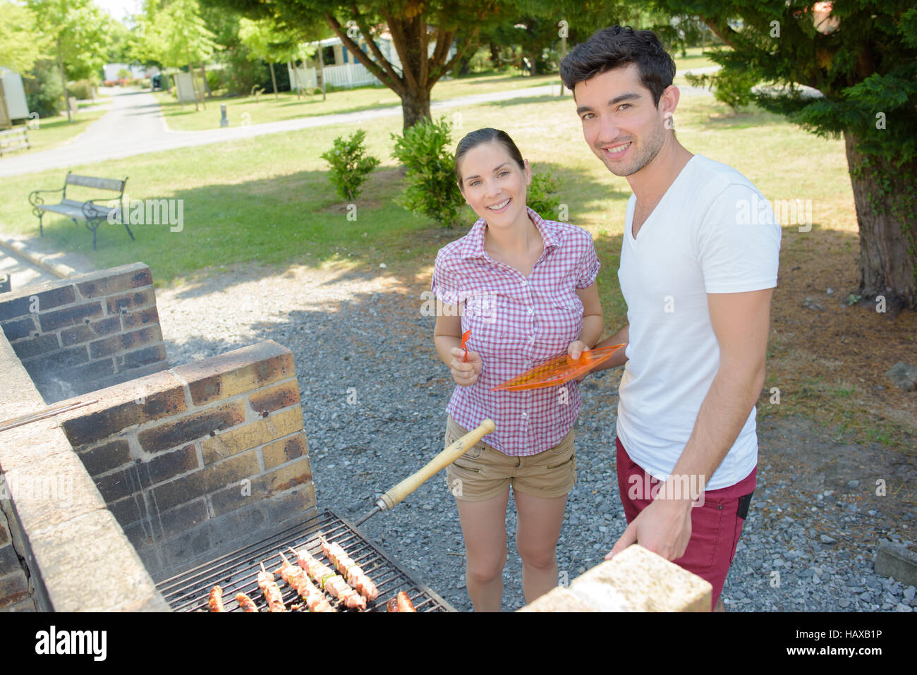 Couple cooking on a barbeque Stock Photo - Alamy