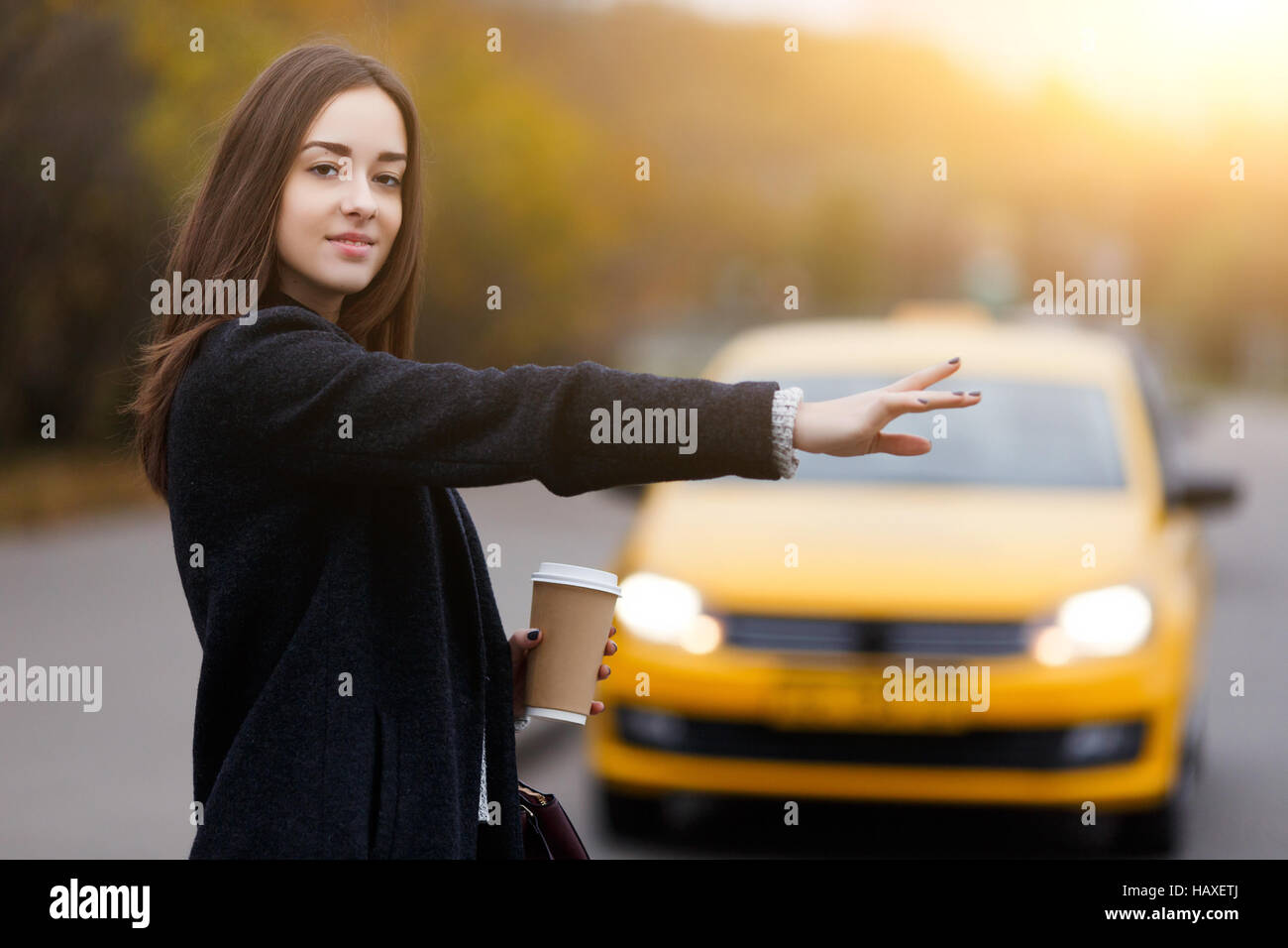 Brunette woman hand gesture catches taxi. Model looking at camera Stock ...