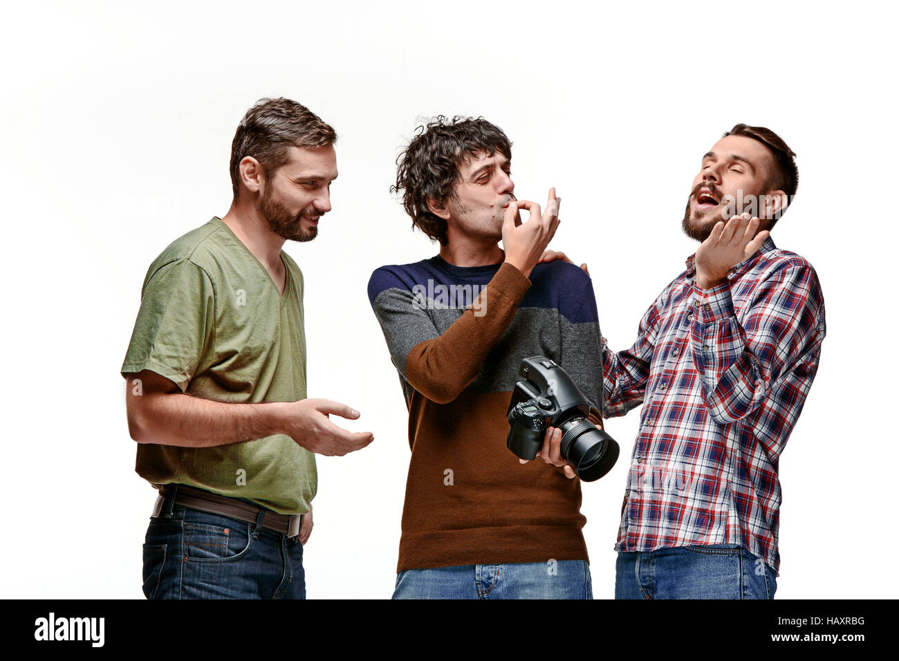 The three male friends with camera on white studio background Stock ...