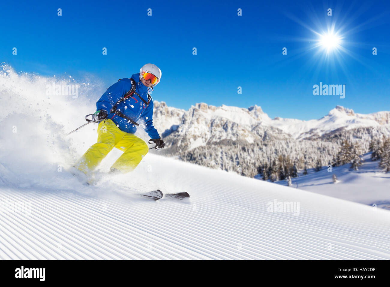 Skier on piste running downhill in beautiful Alpine landscape. Blue sky ...