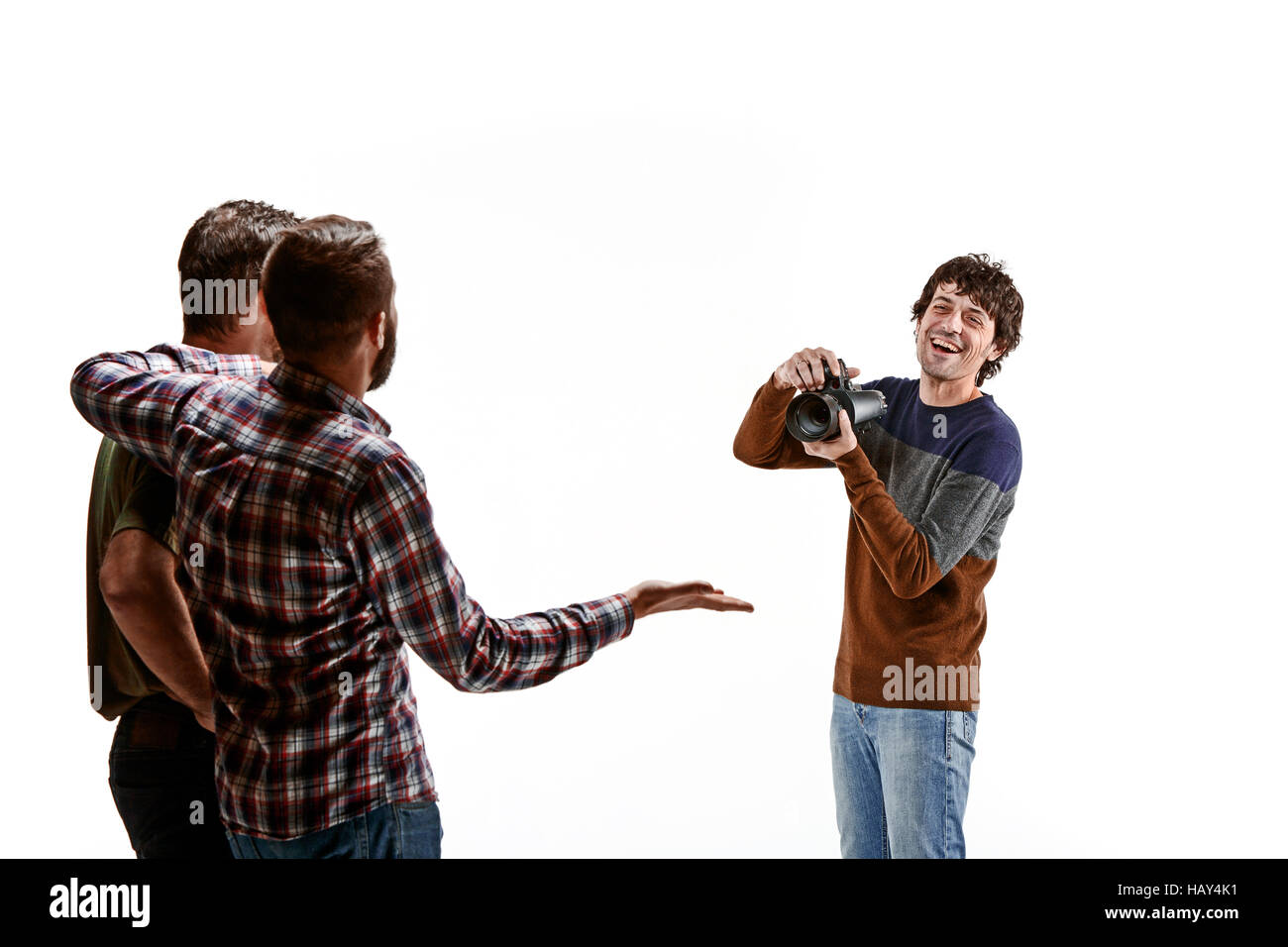 The three male friends with camera on white studio background Stock ...