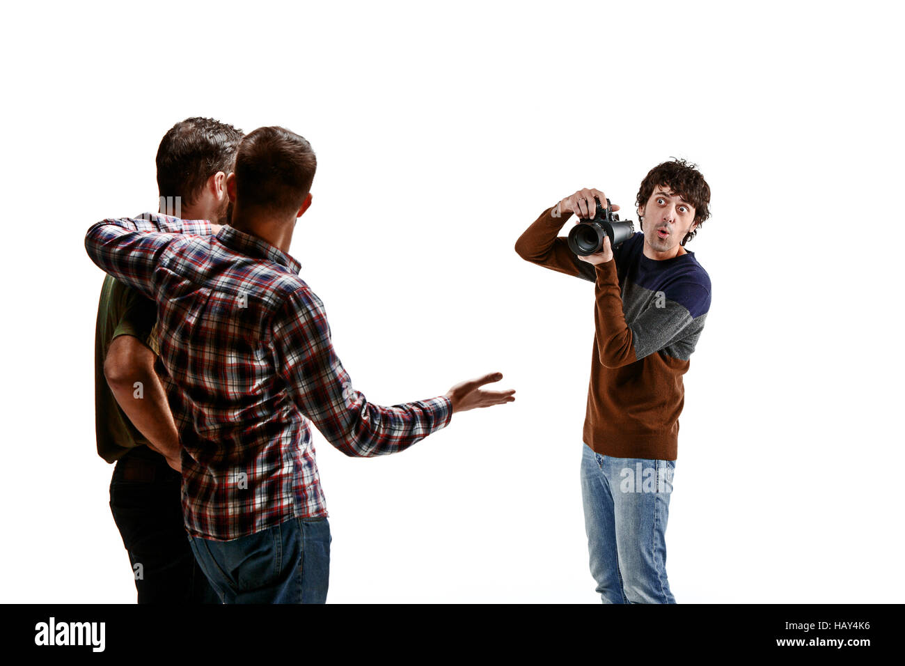 The three male friends with camera on white studio background Stock ...