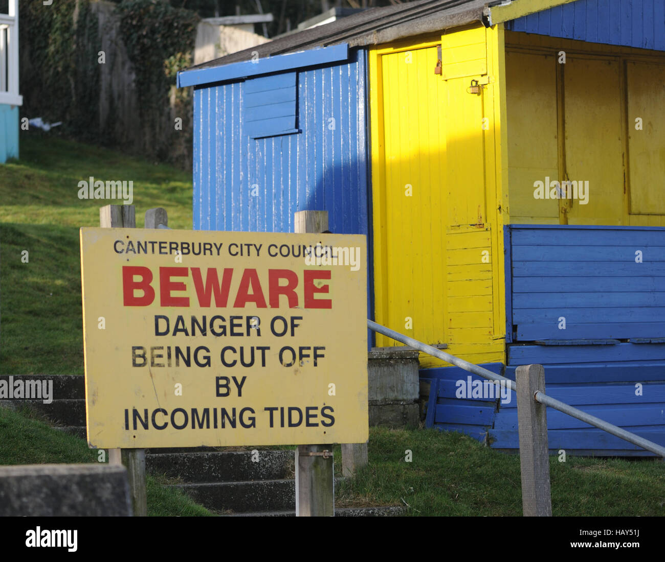 A sign warning about being cut off by incoming tides in front of a blue ...