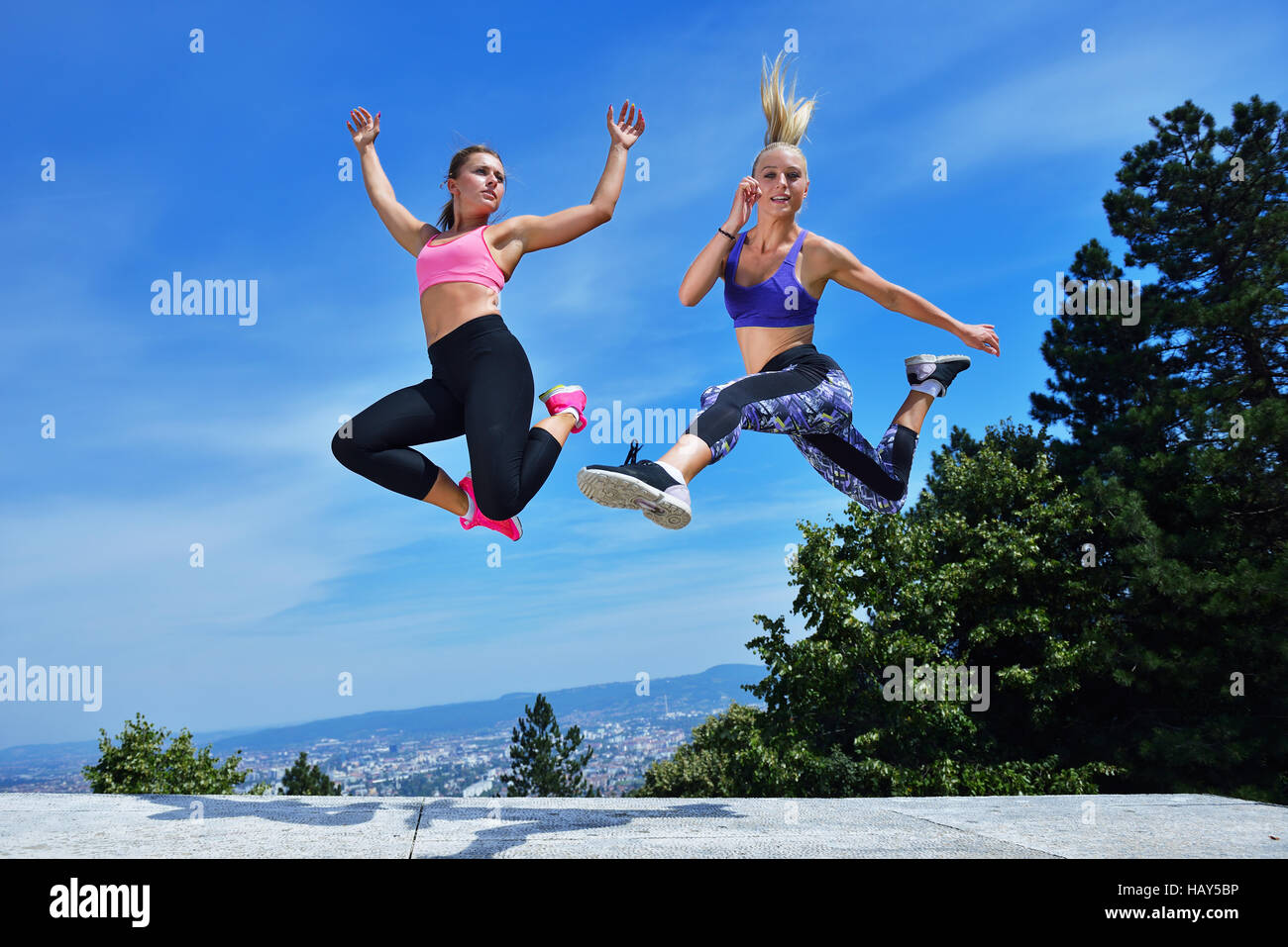 Two happiness young women jumping over blue sky Stock Photo - Alamy