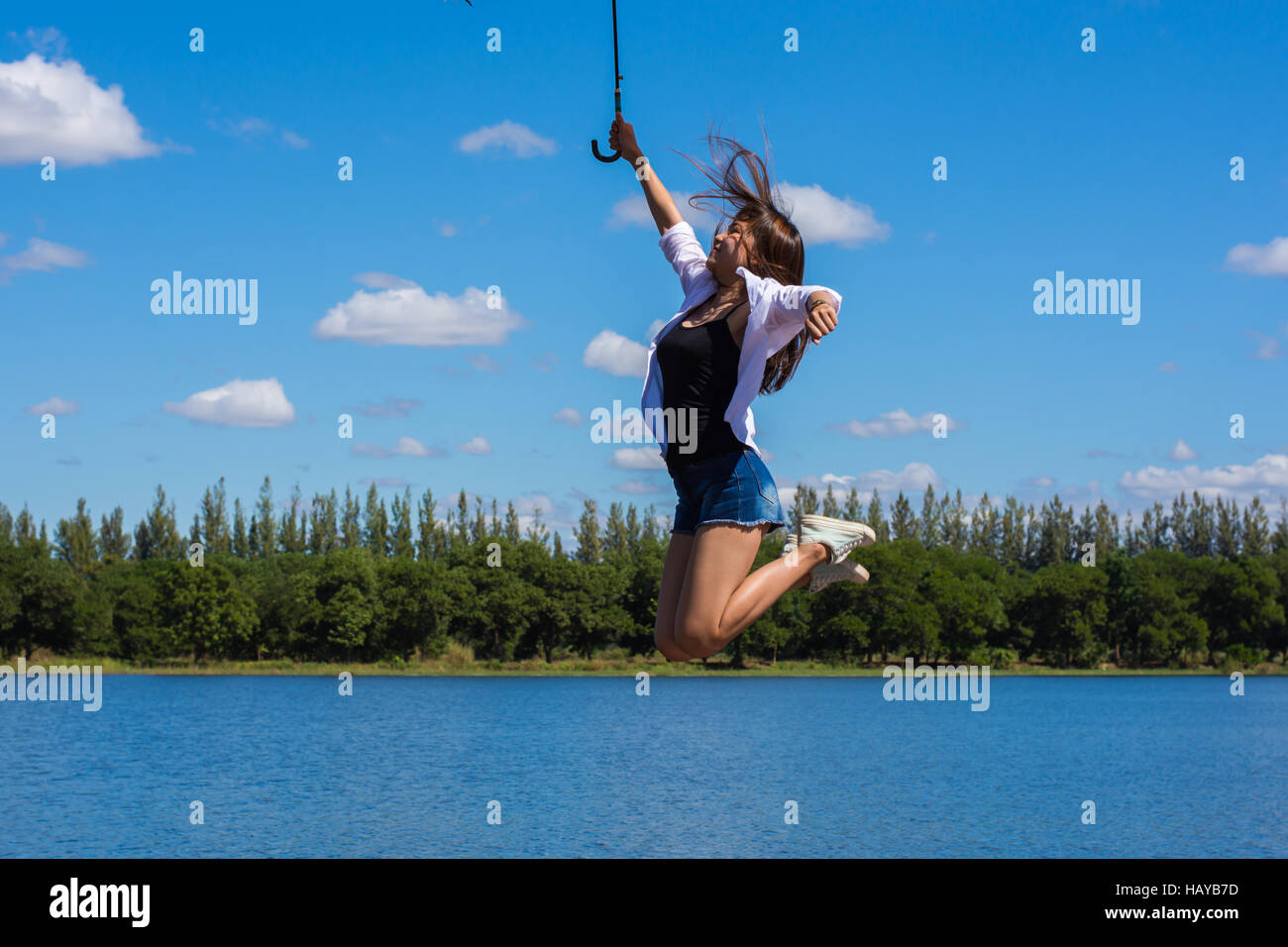 Happy Young Woman Jumping over blue sky on the bench by the pool in the ...