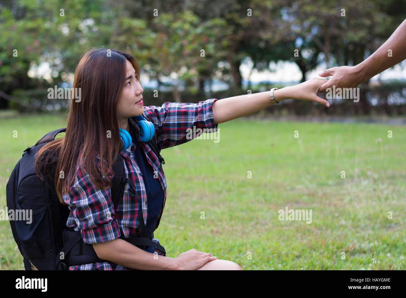 Woman sitting on the grass reaching to shake the hand of man. helping ...