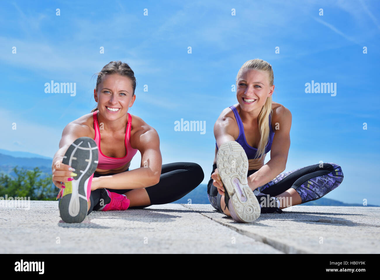 Two pretty women stretching in a park before starting a workout session ...