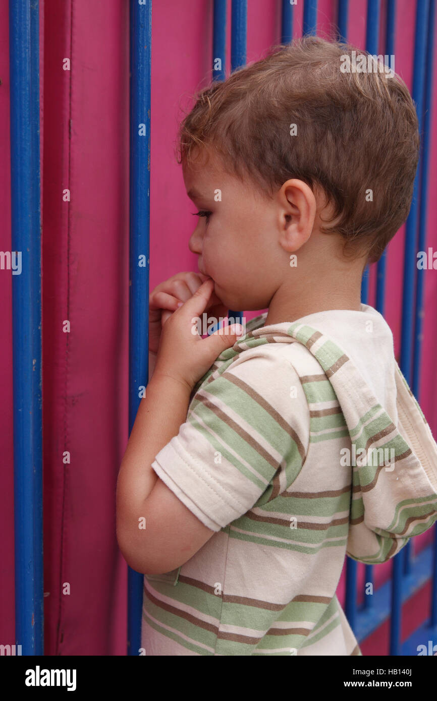 moody little boy standing by colourful gate Stock Photo - Alamy