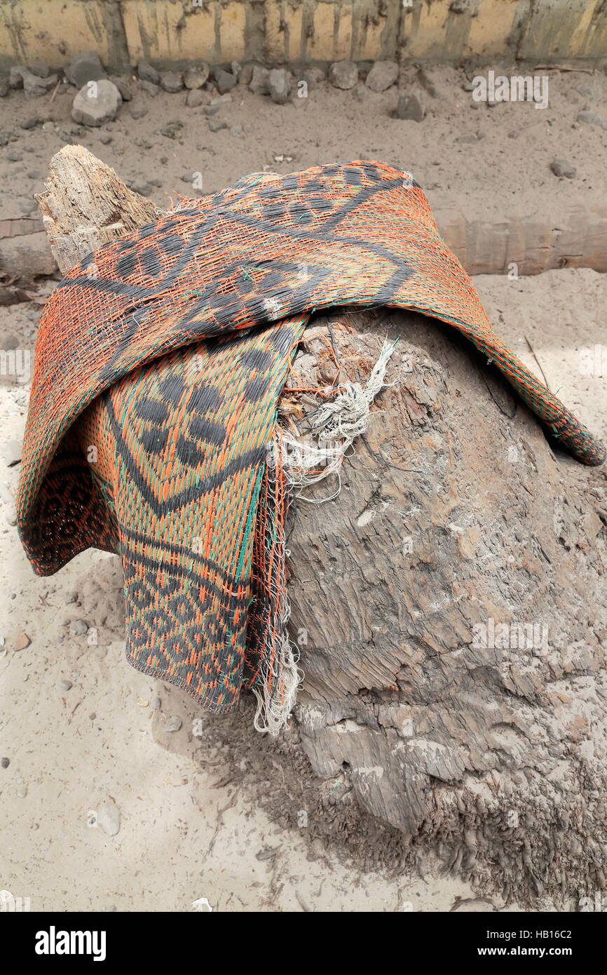 Woven plastic fiber mat set over a dry palm tree stump placed beside a ...