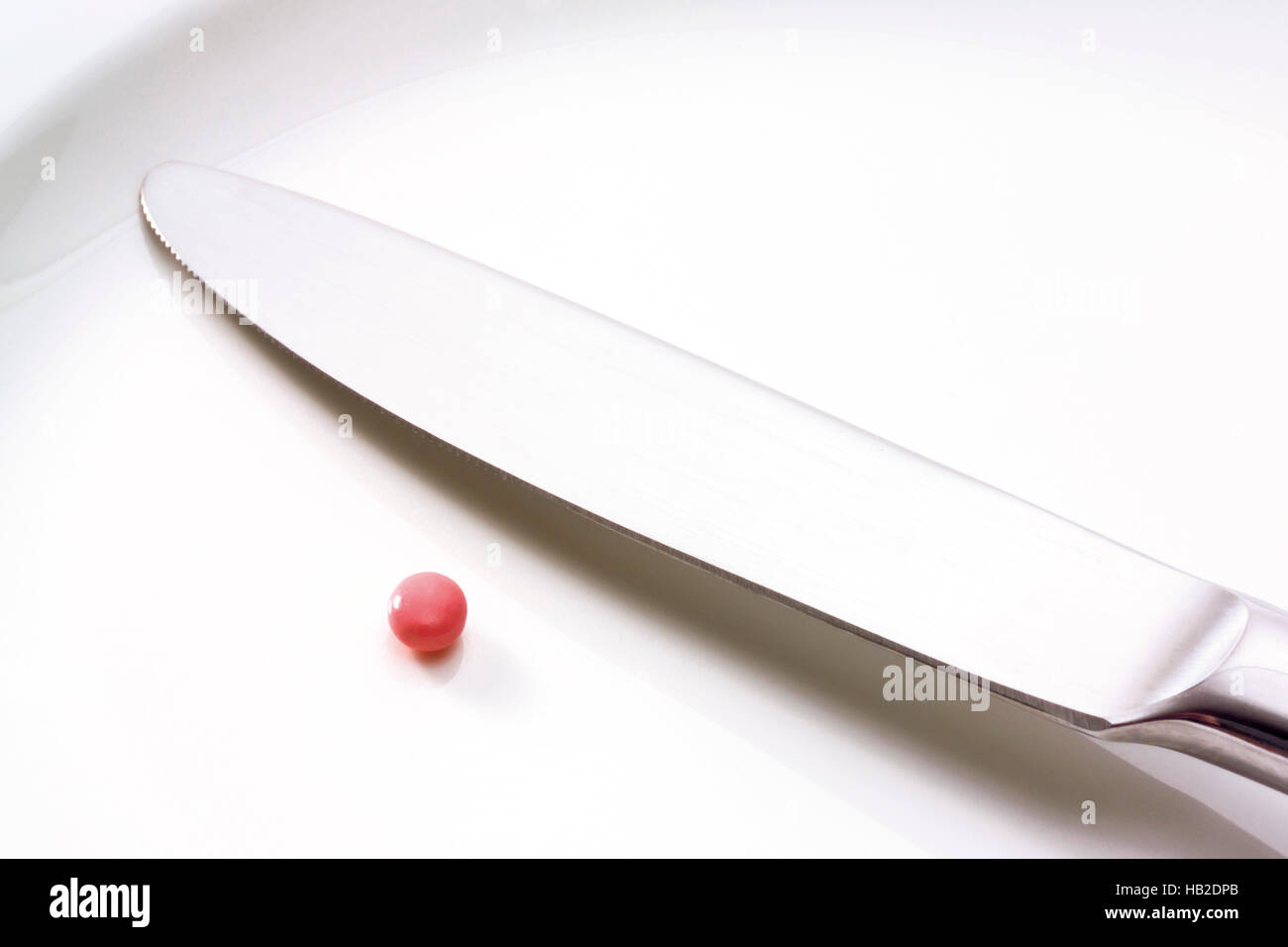 Empty plate with a pill and knife Stock Photo - Alamy