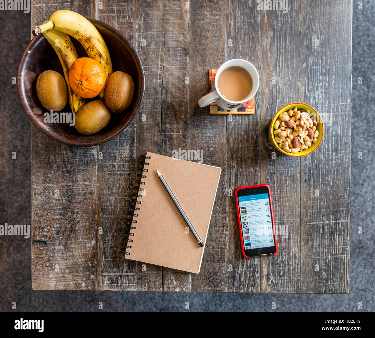 Notes on smartphone, notebook with pen, coffee, fruit and nuts, snacks ...