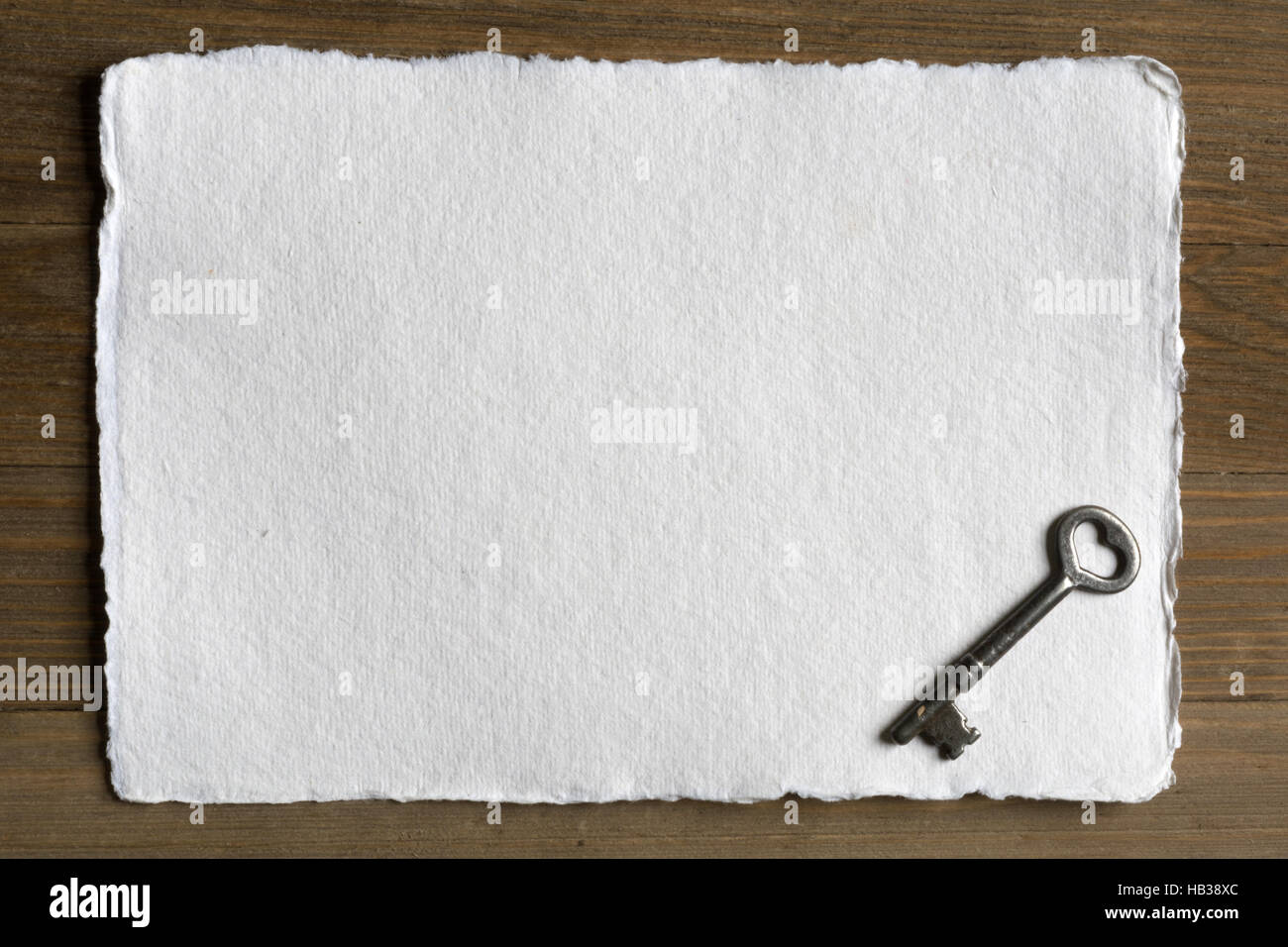 Antique skeleton key with heart shaped opening against blank paper ...