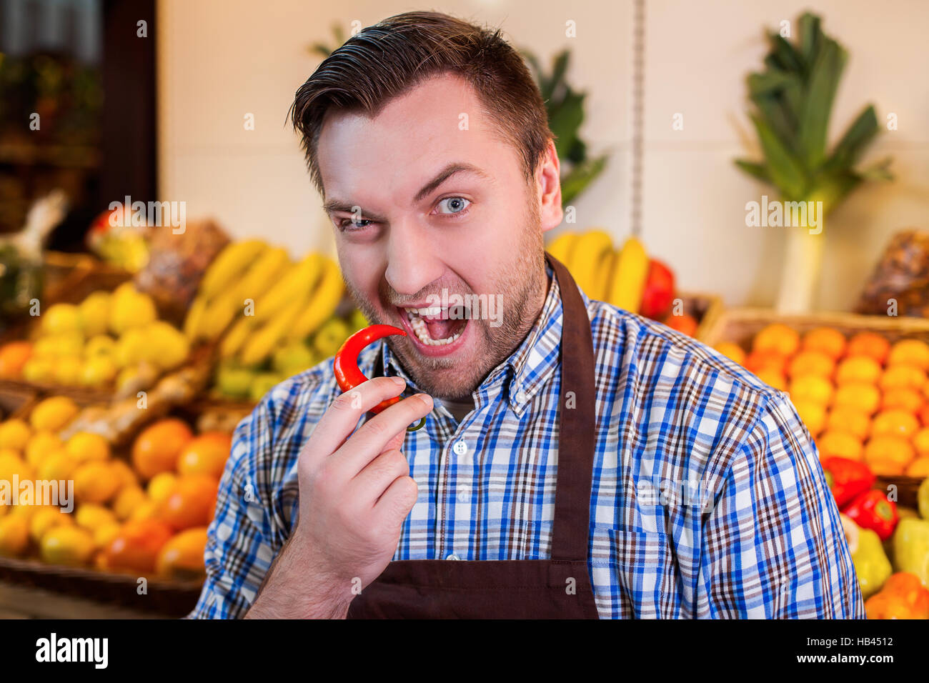 Man trying to eat a chili pepper Stock Photo - Alamy