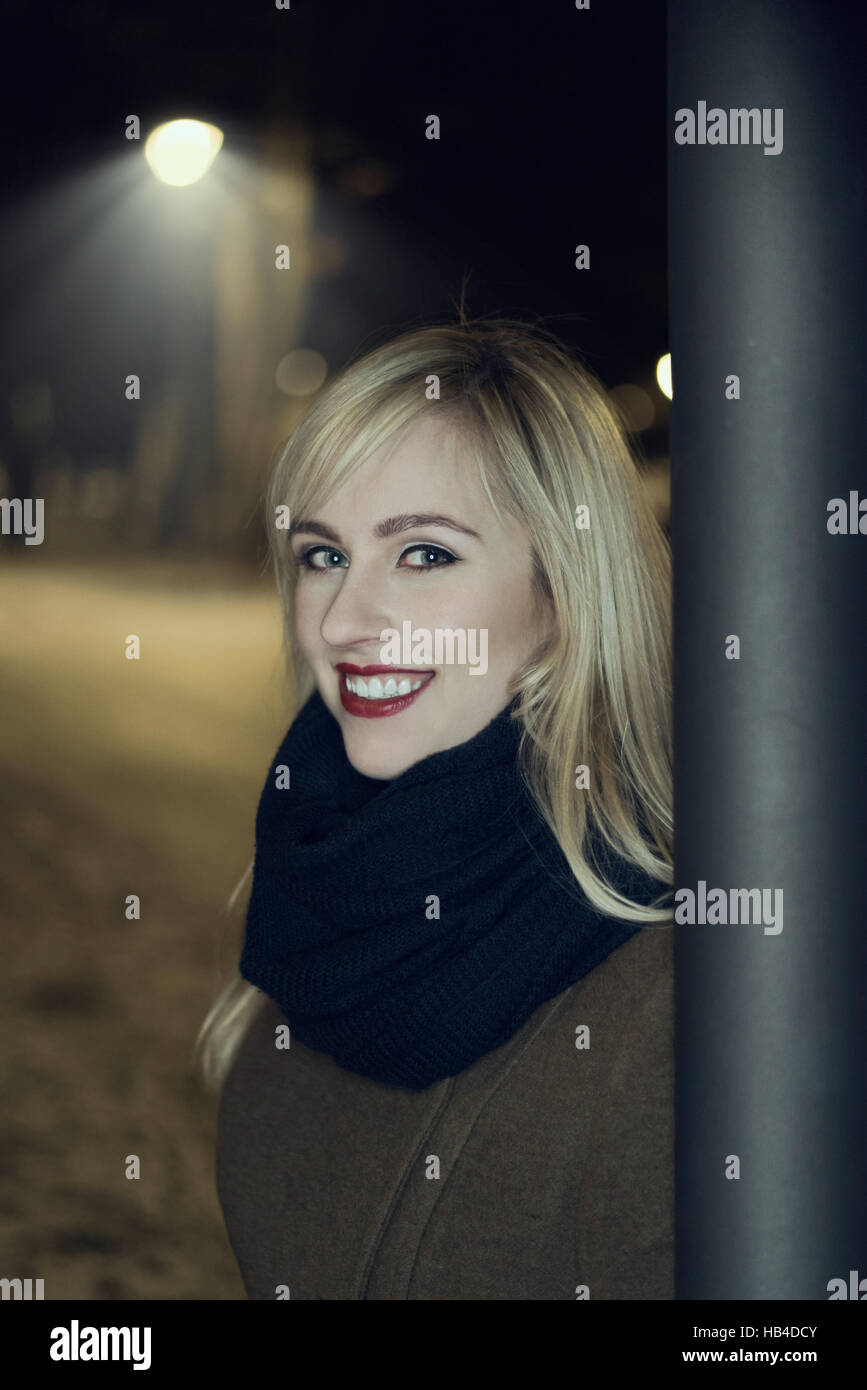 Woman smiling under light source in park at night Stock Photo - Alamy