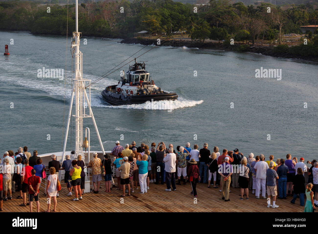 Cruise ship passengers on deck watch as a Panama Canal tugboat passes ...