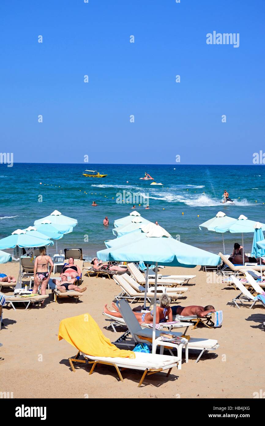 Tourists relaxing on the beach with views towards the sea, Stalida ...