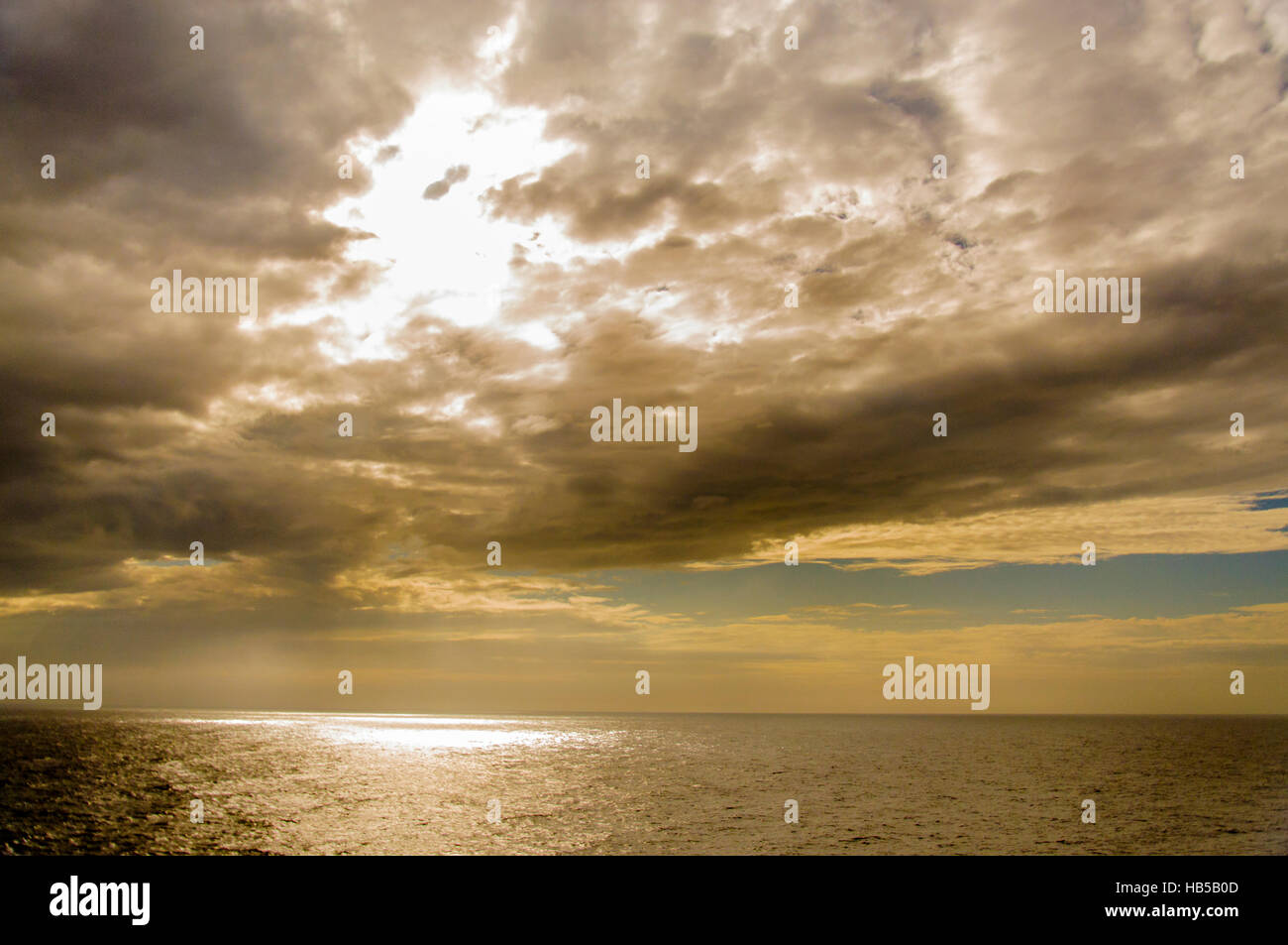 Sun breaking through clouds at sea Stock Photo - Alamy