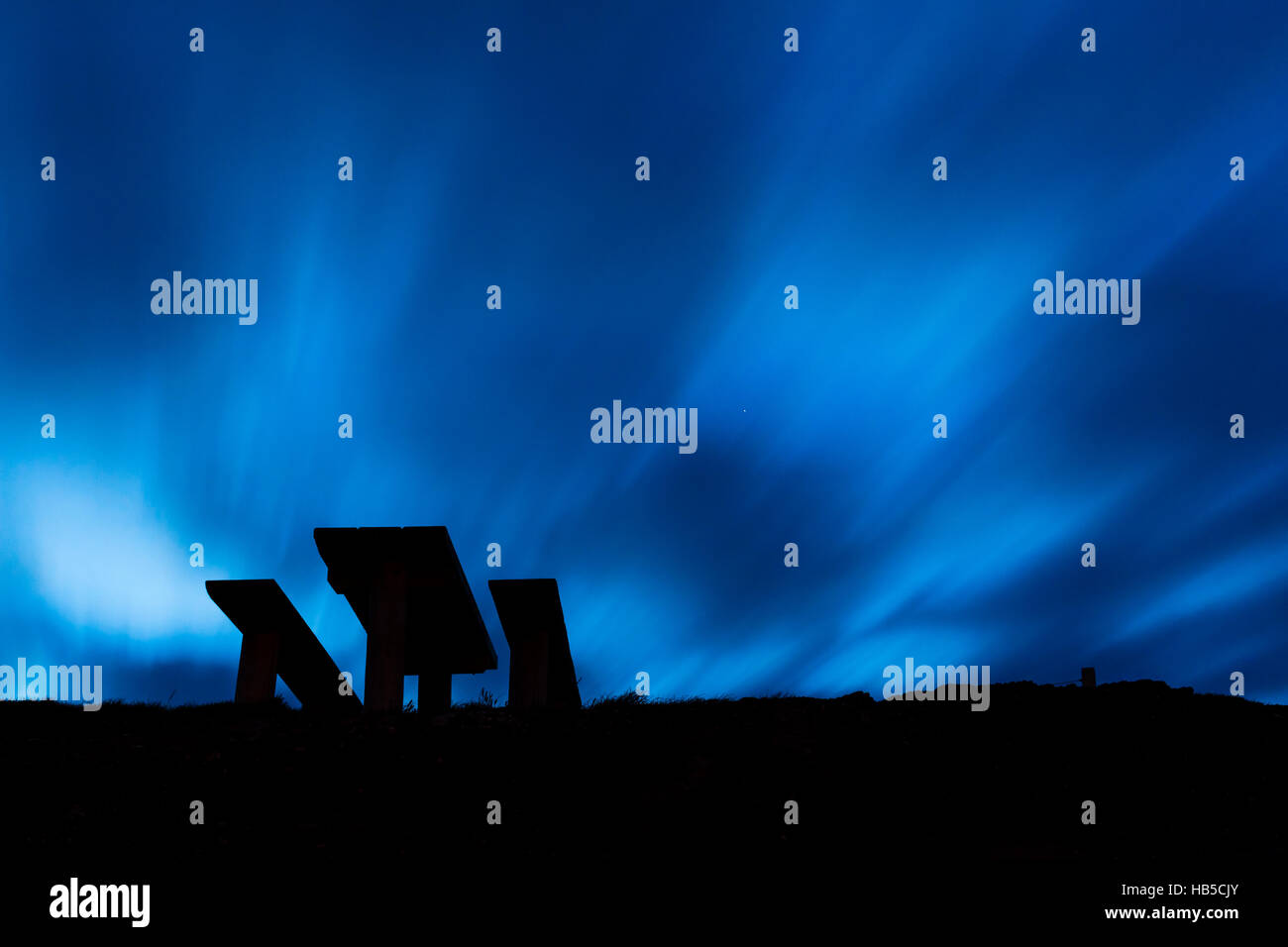 Silhouette of picnic bench under a cloudy moonlit night sky in Fenit ...