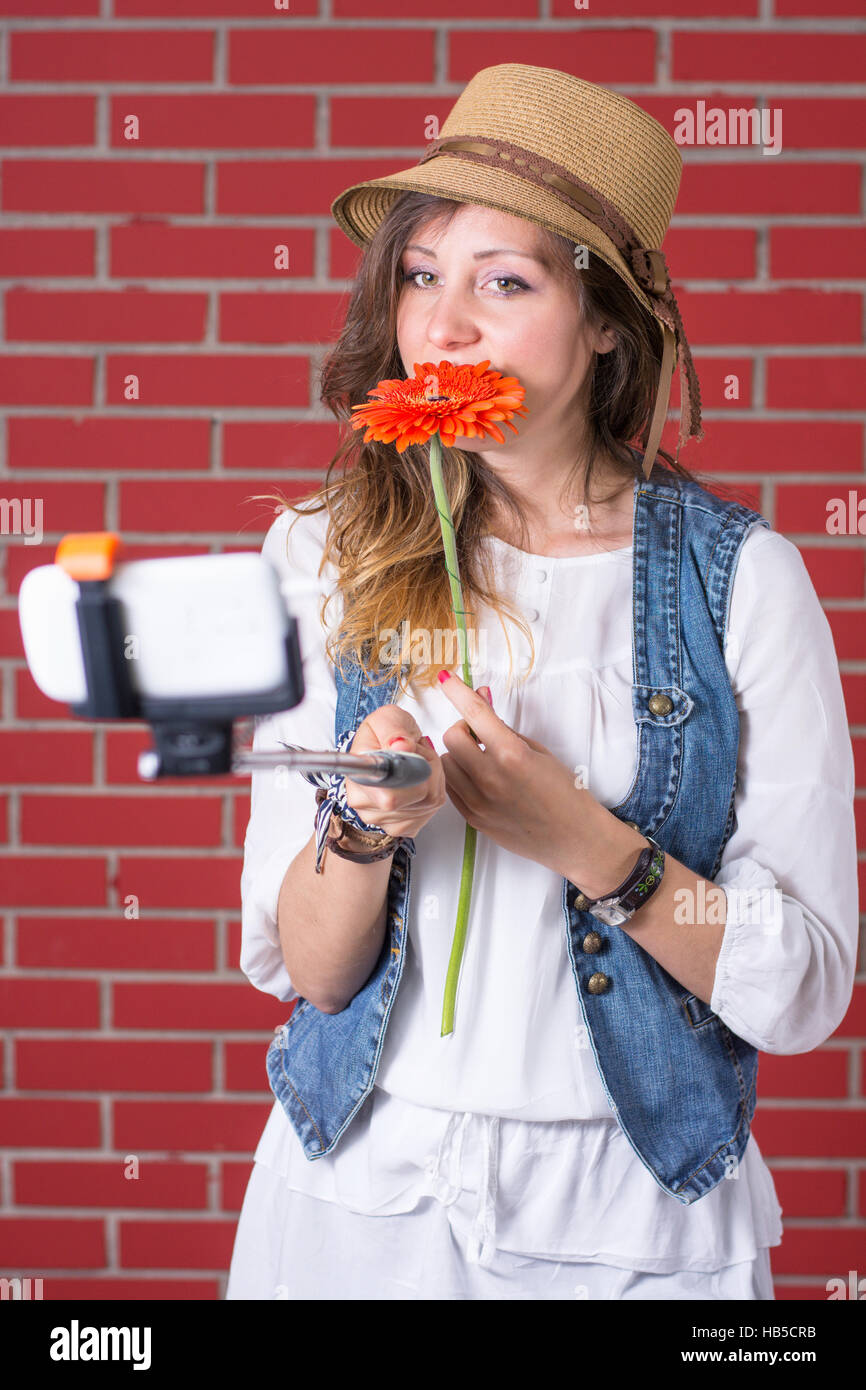 Female using selfie stick in front of brick wall Stock Photo - Alamy