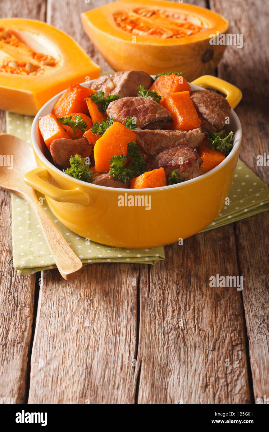Beef stew with pumpkin, onion and spices close up in a yellow pan on ...