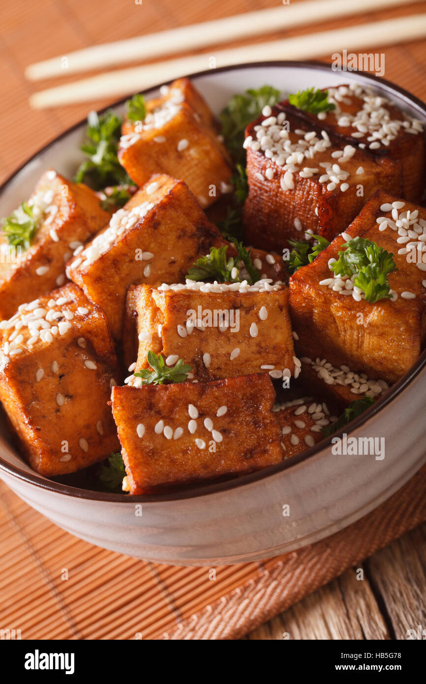 Vegetarian tofu fried with sesame seeds and herbs in a bowl close-up ...