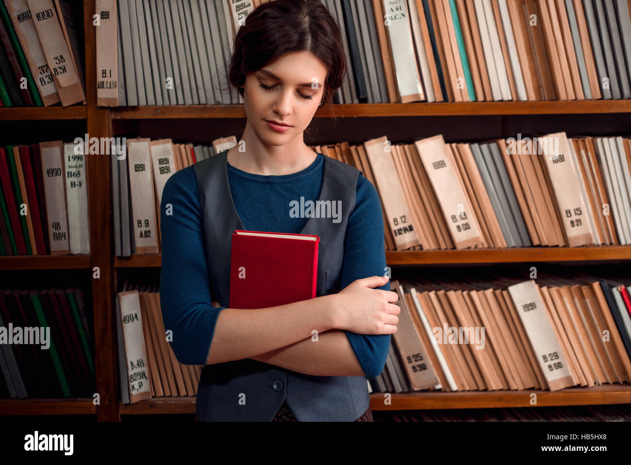 Student standing with eyes closed in library Stock Photo - Alamy