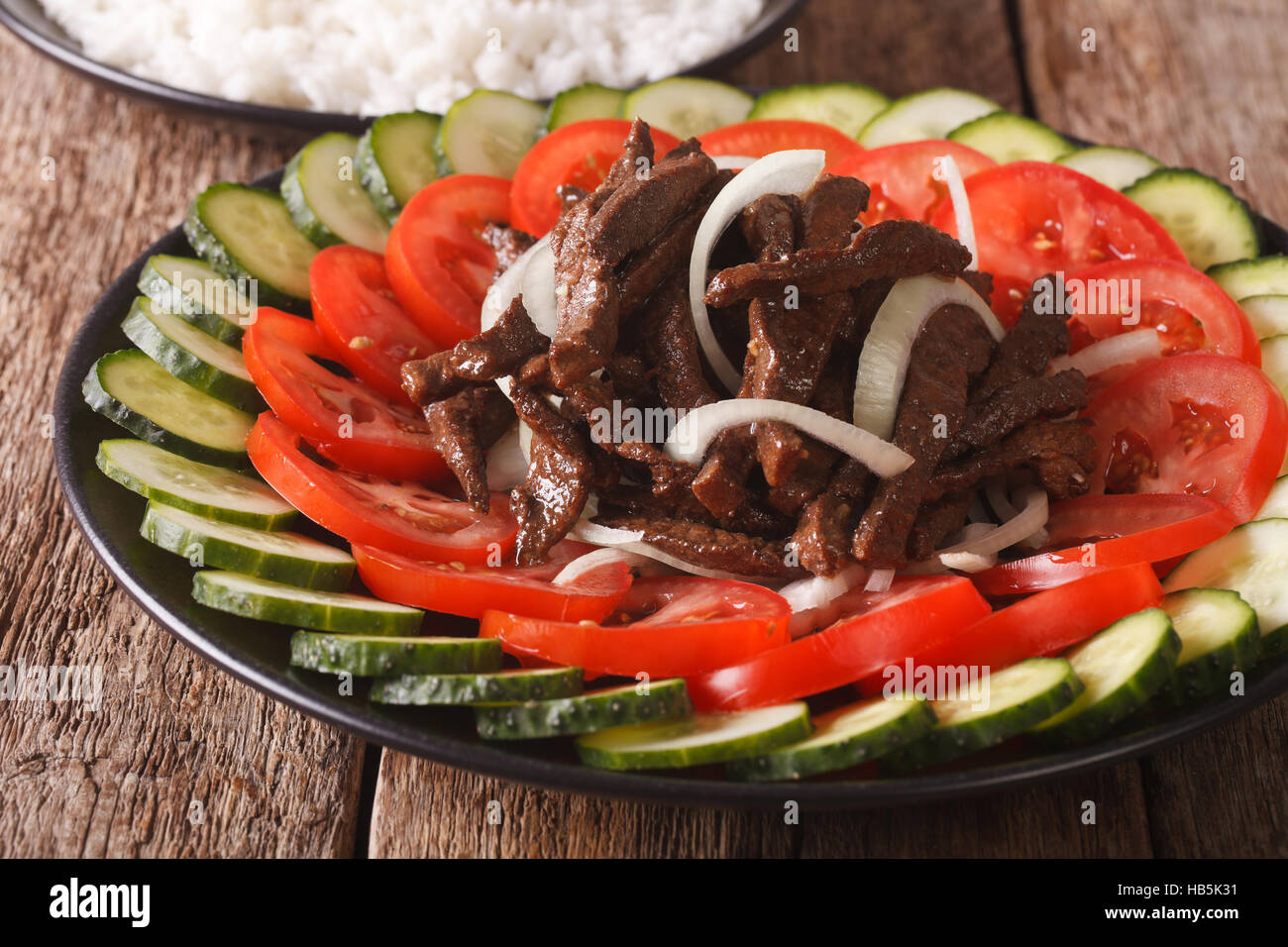 Cambodian beef Lok Lak with fresh vegetables close-up on a plate ...