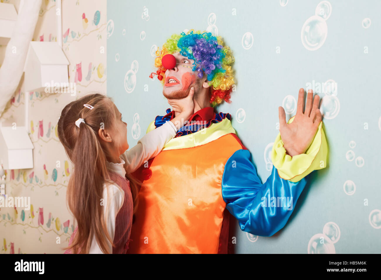 Cruel girl playing with scared clown Stock Photo - Alamy