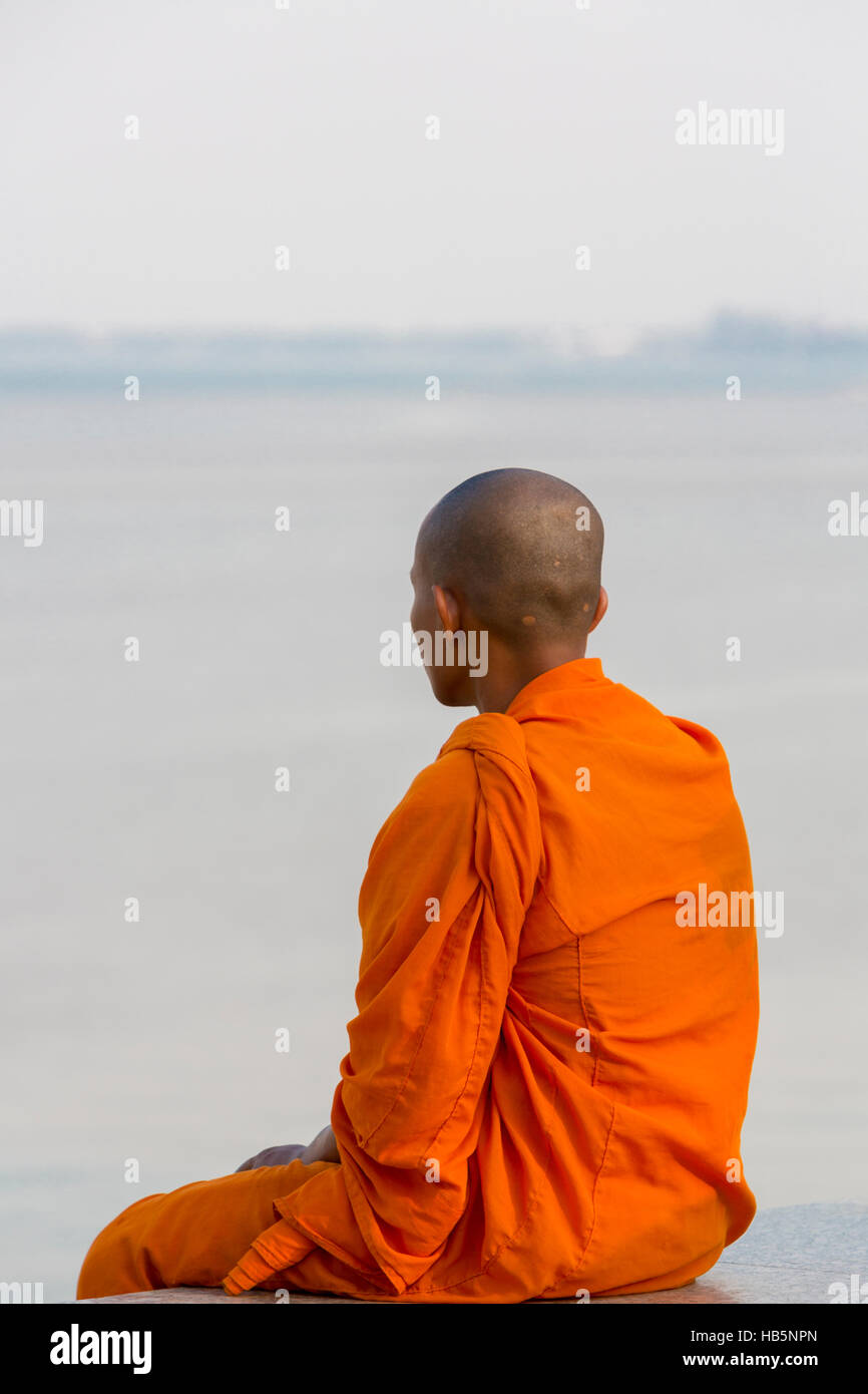 Orange dressed Cambodian monk looking at the Mekong, Phnom Penh Stock ...