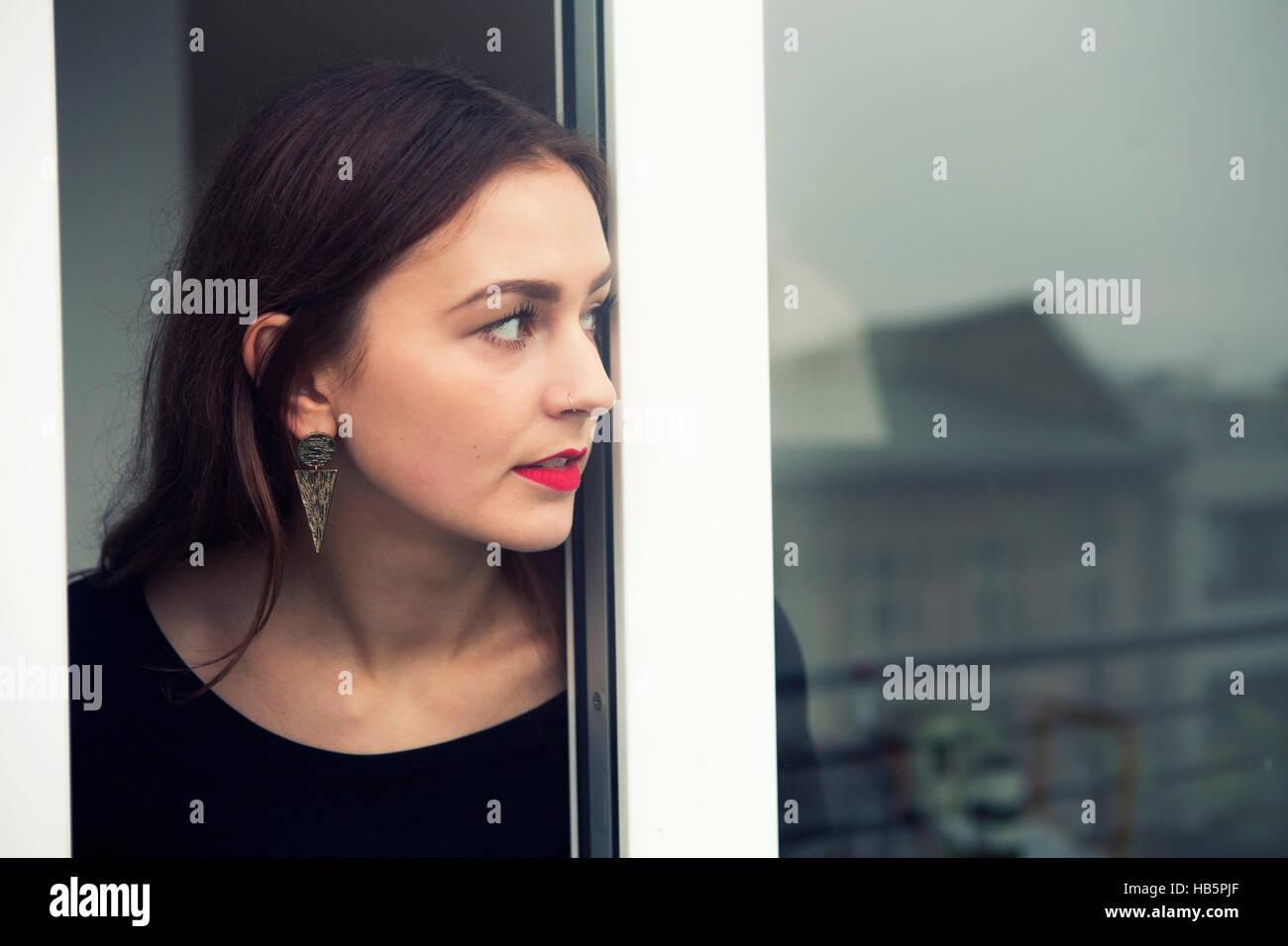 portrait of beautiful brunette young woman looking out of window Stock ...