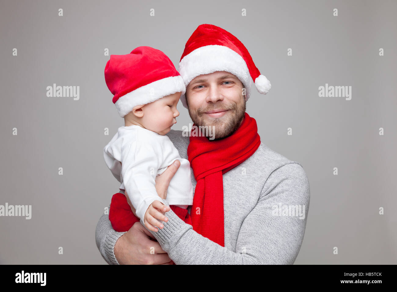 Father with his baby boy wearing Santa hats celebrating Christmas Stock ...