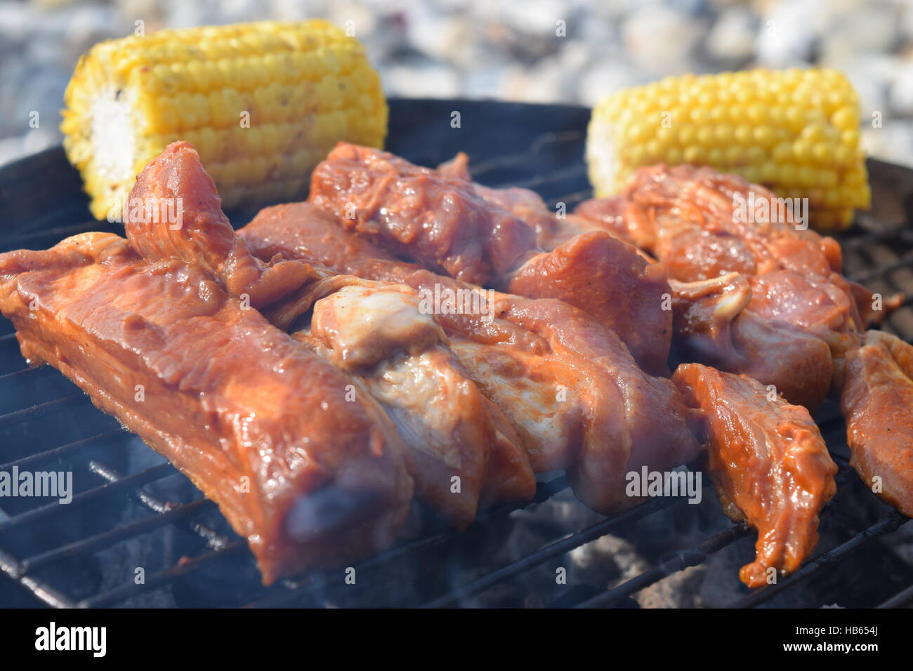 Close-up of juicy ribs on a hot barbecue with sweetcorn Stock Photo - Alamy