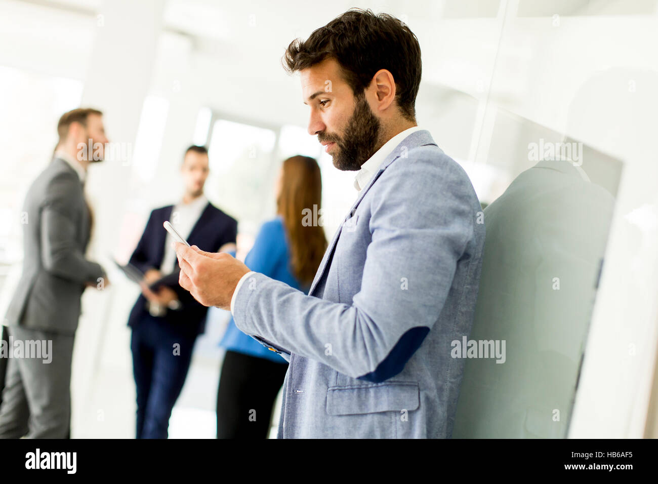 Businessman using mobile phone in office while other business people ...