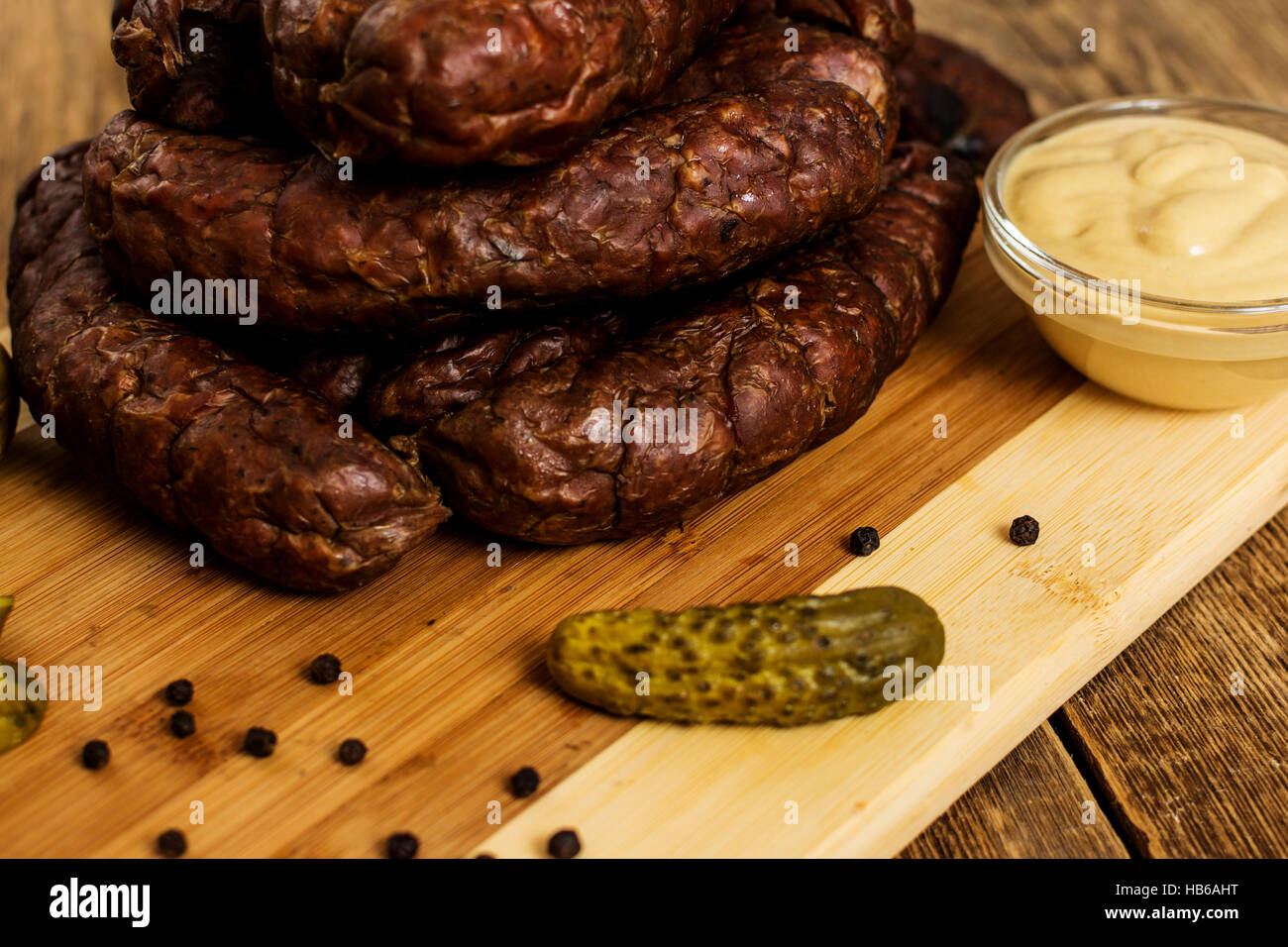 traditional homemade smoked pork sausage with gherkin on wood table ...
