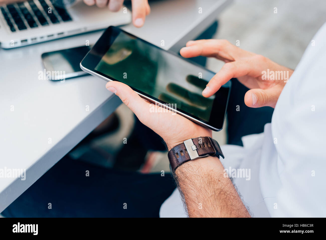Close up on the hands of two men using technological devices, tapping ...