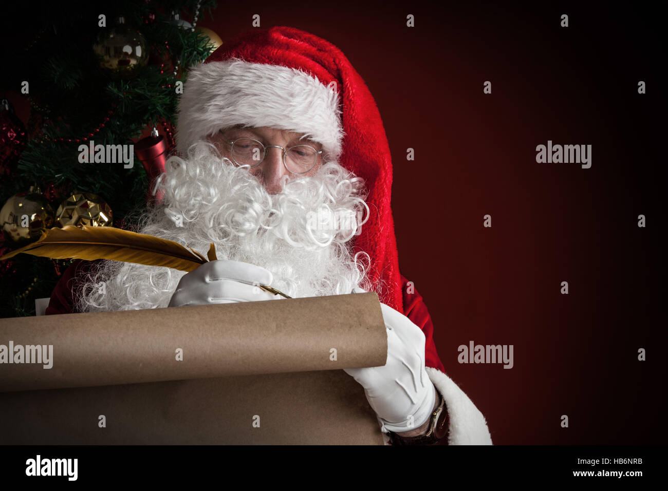Santa Claus writing on old paper roll list with quill pen Stock Photo ...
