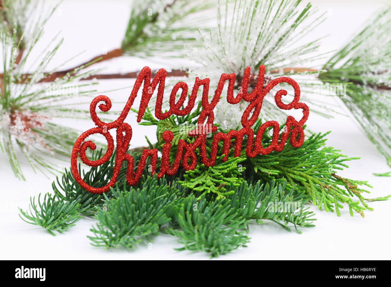 Merry Christmas written with letters covered in red glitter on pine ...