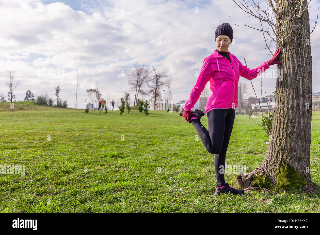 Young woman warming up and stretching the legs before running on a cold ...