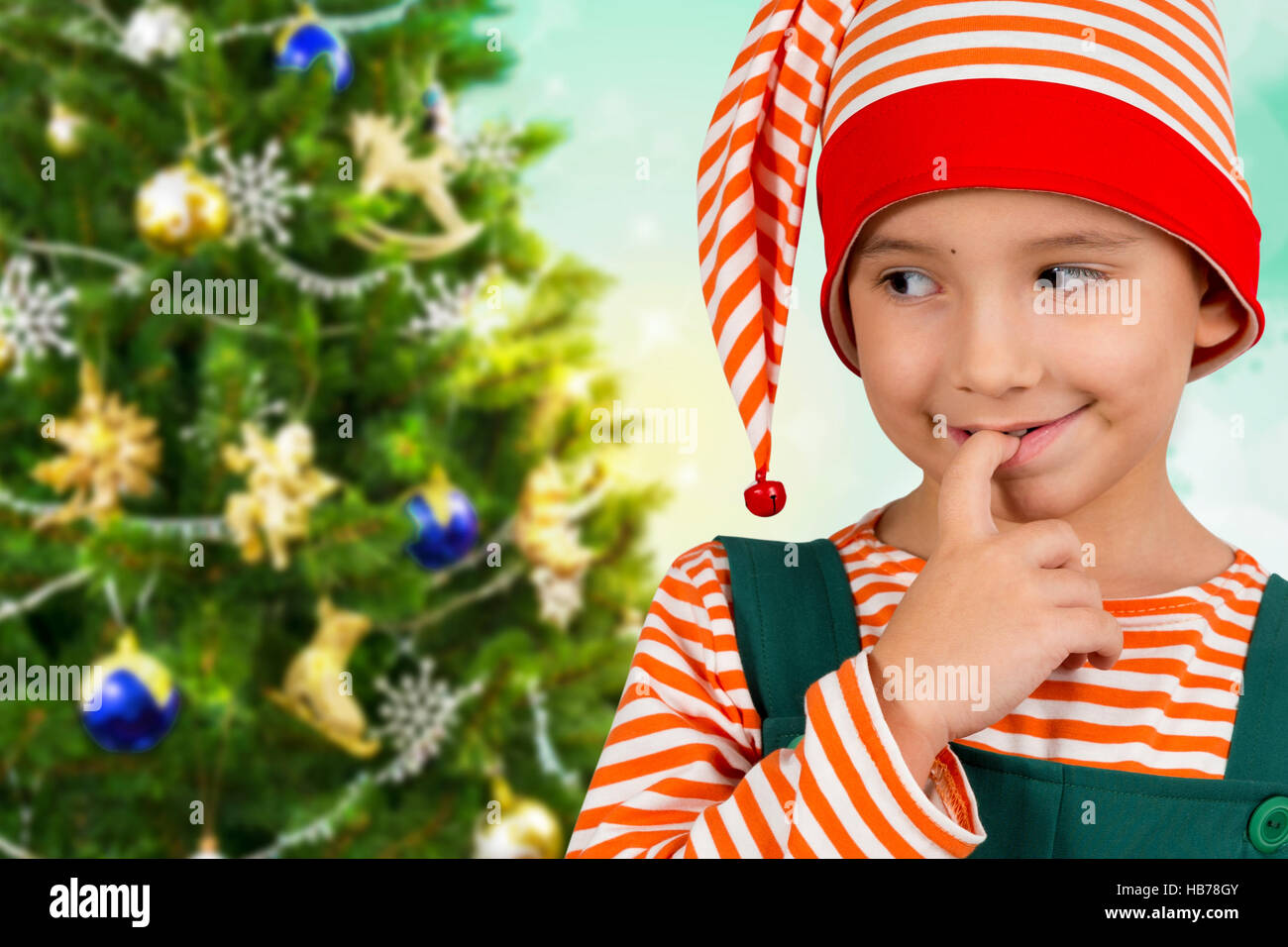 Portrait of a child in an elf suit on the background of Christmas tree ...