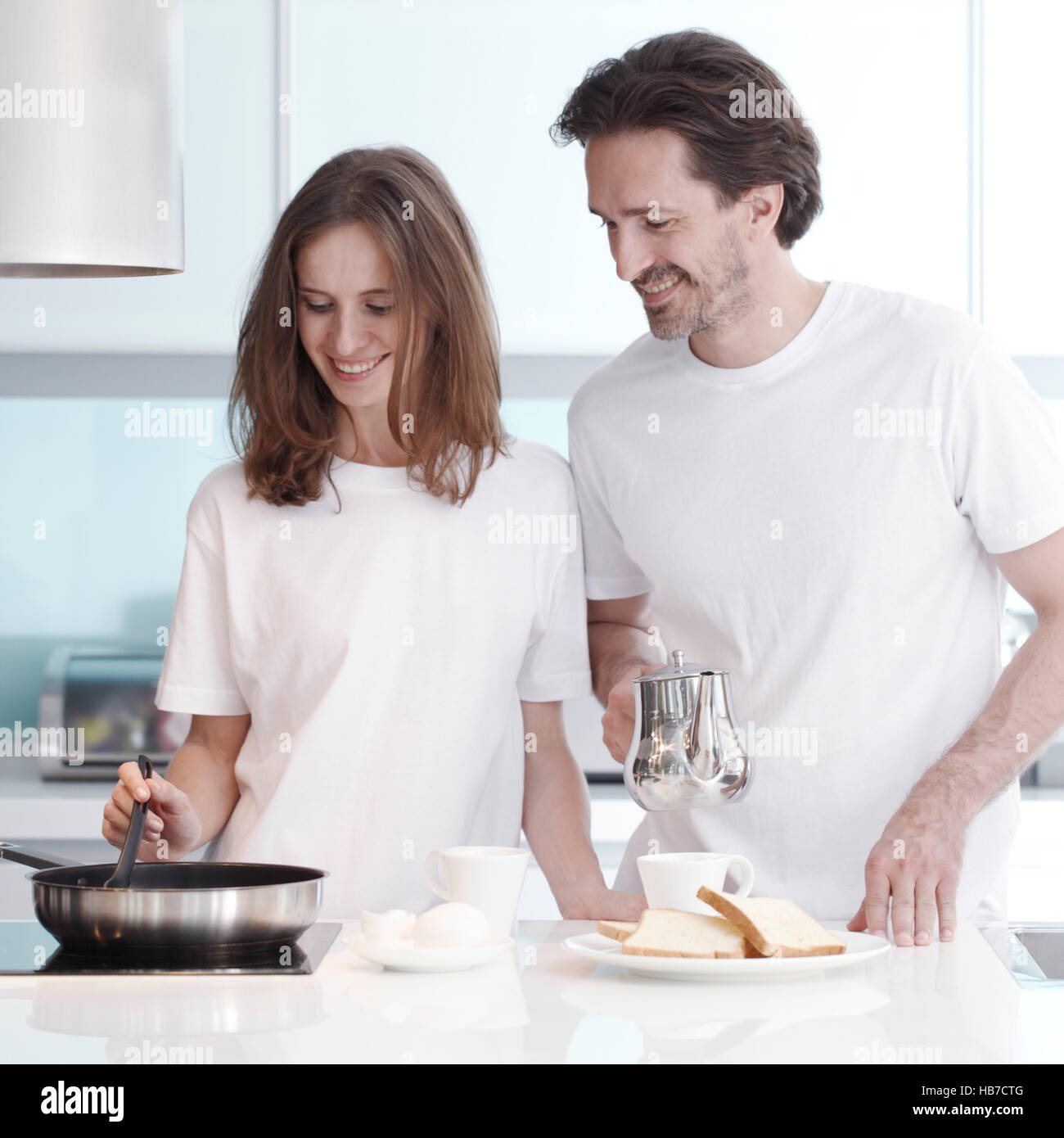 Happy couple cooking breakfast together in the kitchen Stock Photo - Alamy