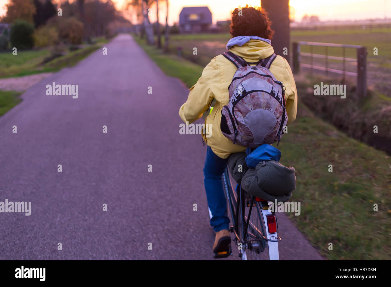 Traveler biking alone in the sunset Stock Photo - Alamy