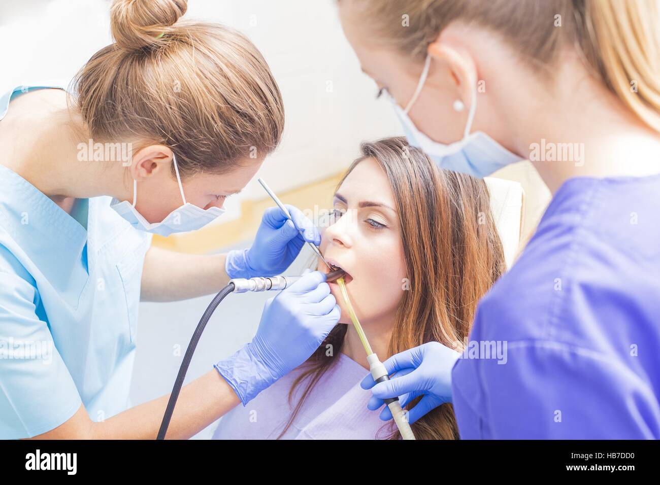 Dentist filling woman's teeth and assistant helping out Stock Photo - Alamy