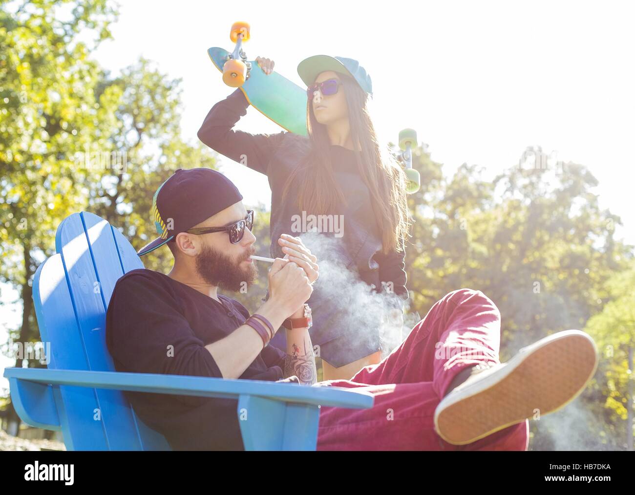 Hipster couple taking a break and smoking on bench Stock Photo - Alamy