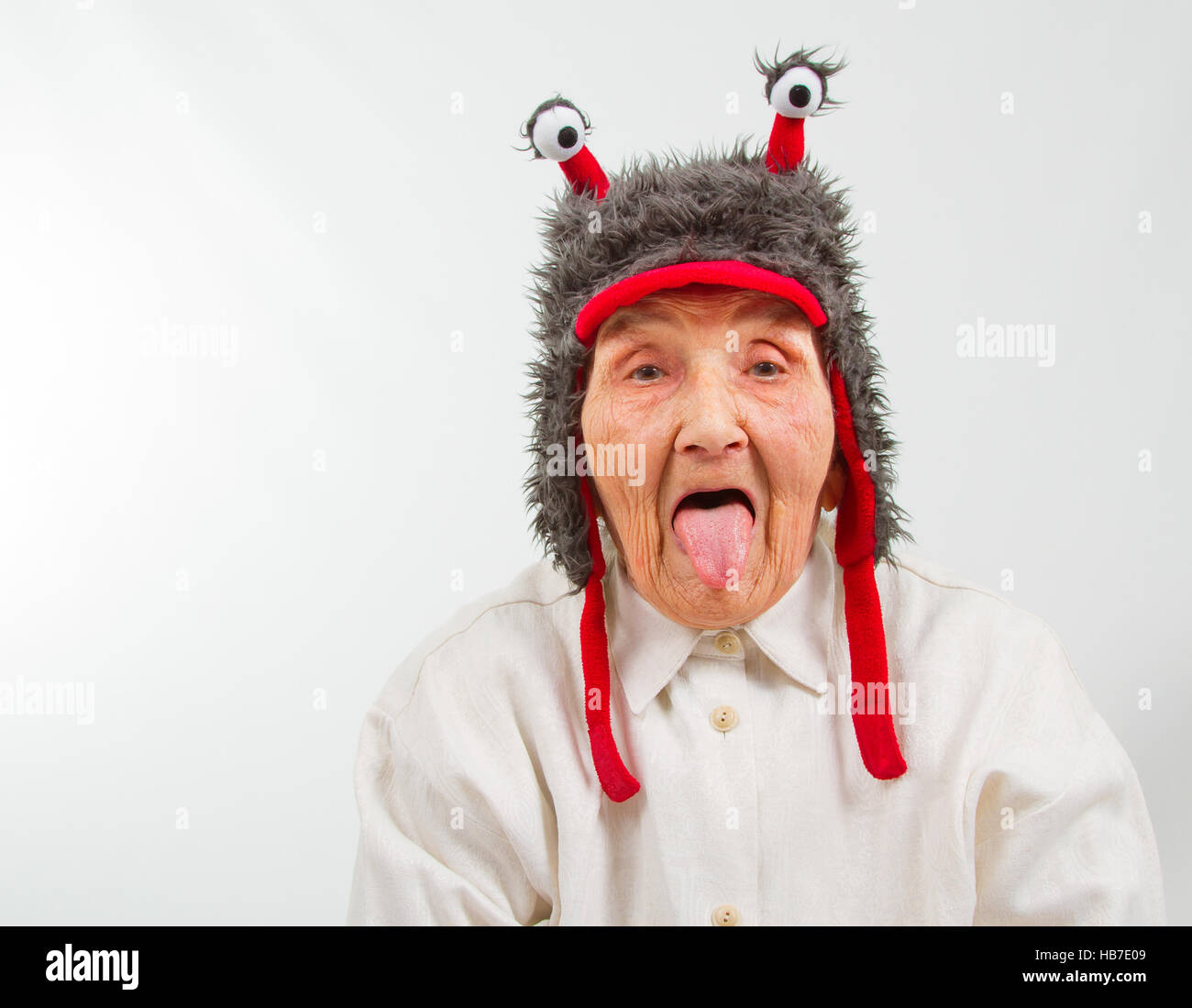 very old lady in funny fur hat with two tentacles puts out her tongue ...