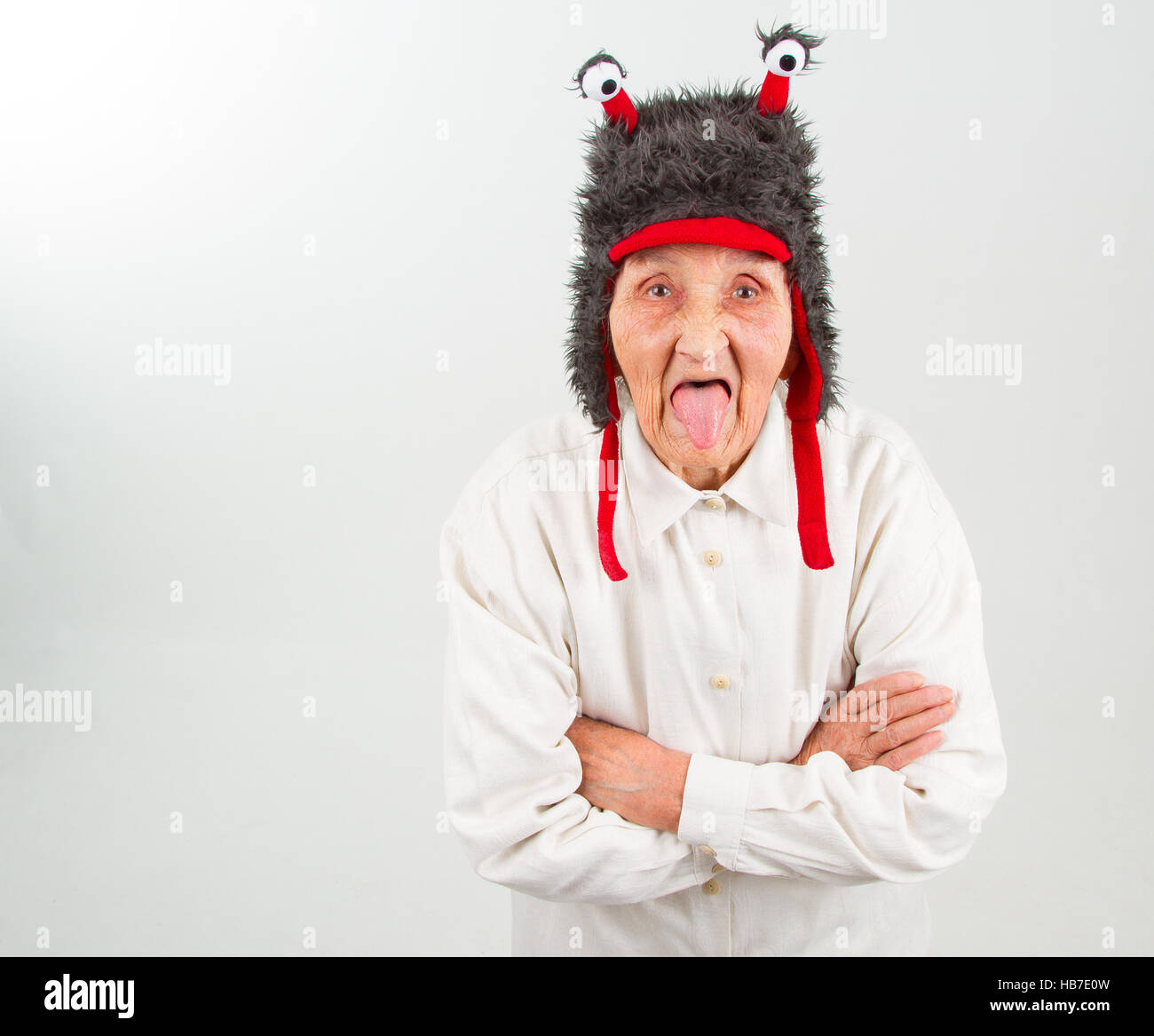 very old lady in funny fur hat with two tentacles puts her tongue out ...